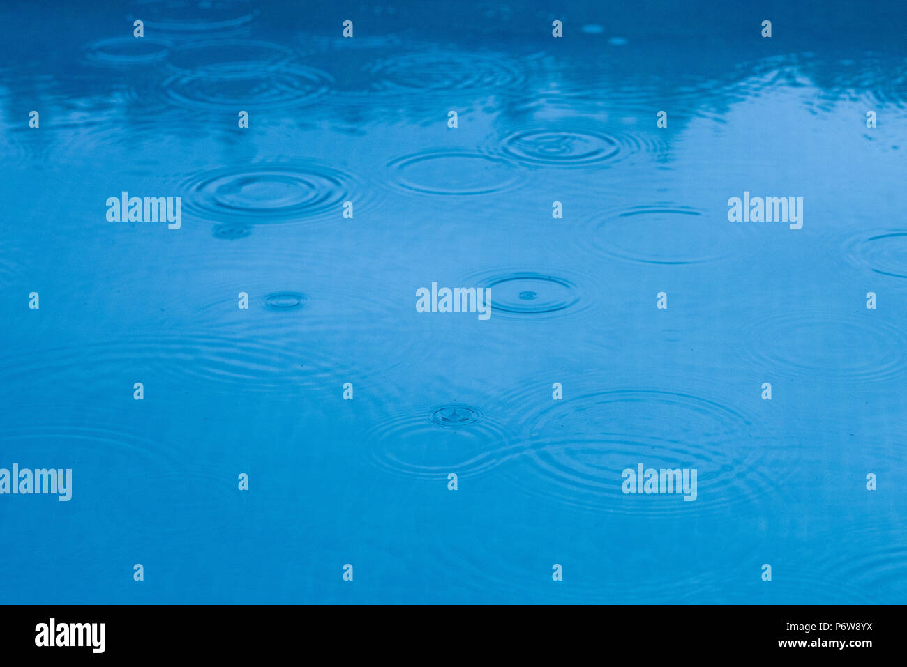 Raindrops falling on a pool or blue lake Stock Photo - Alamy