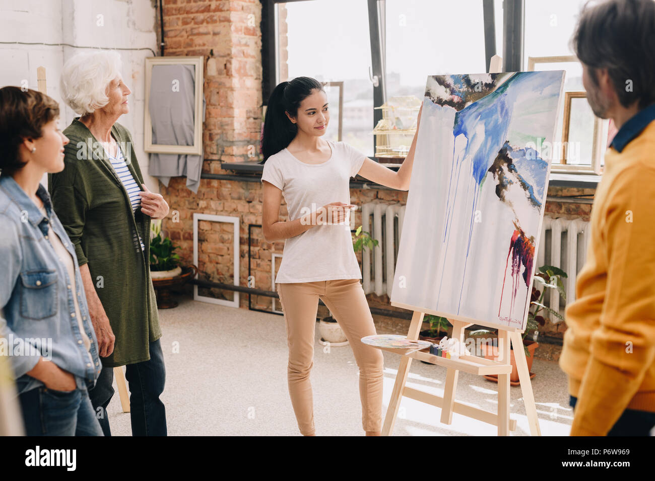 Portrait of pretty young woman presenting modern watercolor painting to ...