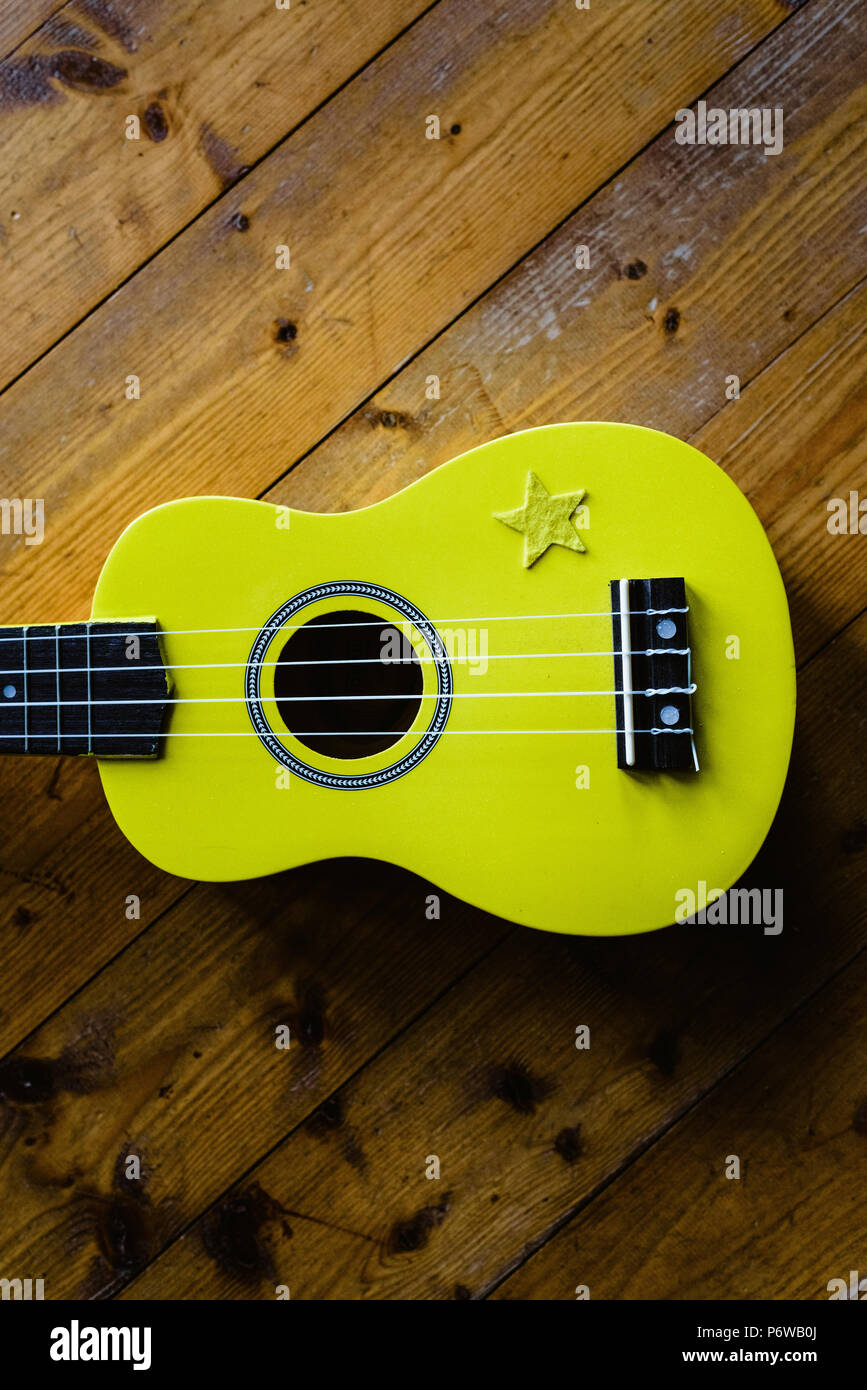 Small yellow ukulele on wooden floor ready to be played Stock Photo - Alamy