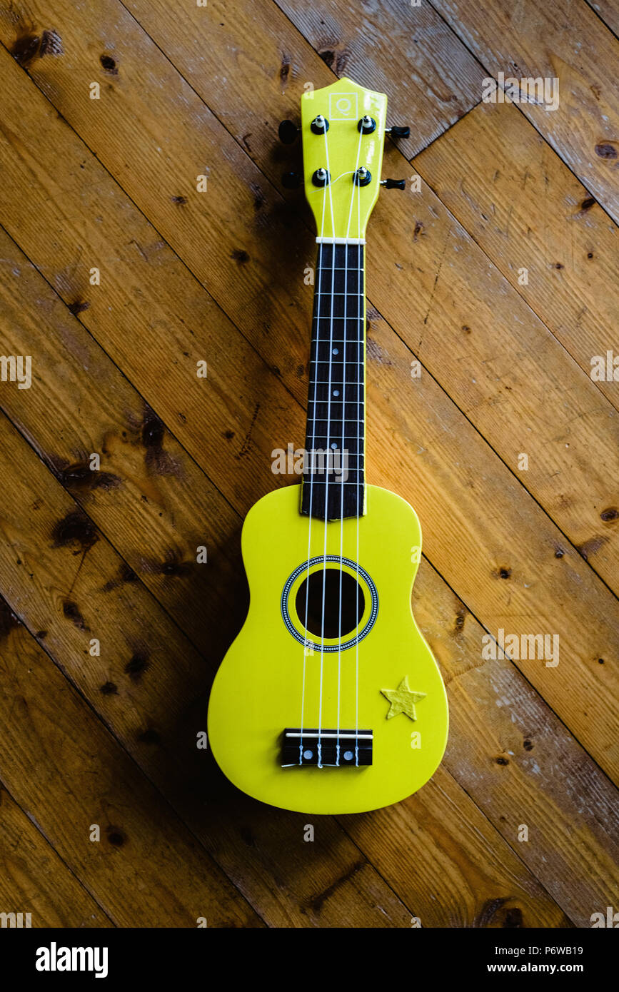 Small yellow ukulele on wooden floor ready to be played Stock Photo - Alamy