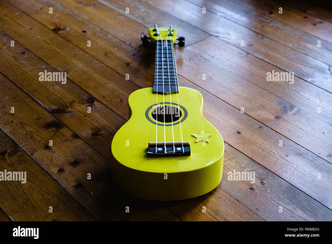 Small yellow ukulele on wooden floor ready to be played Stock Photo - Alamy