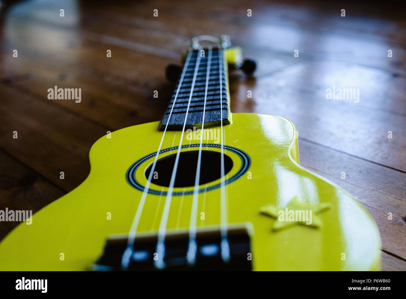 Small yellow ukulele on wooden floor ready to be played Stock Photo - Alamy