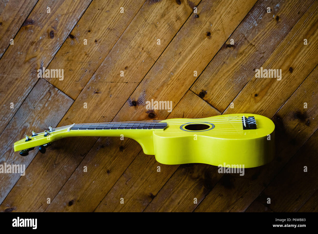 Small yellow ukulele on wooden floor ready to be played Stock Photo - Alamy