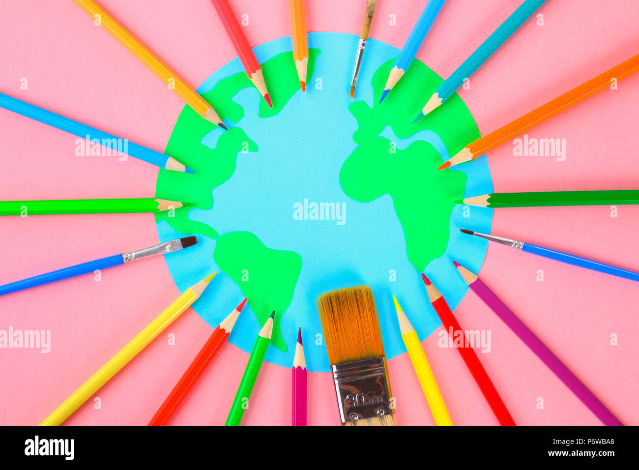 World art. Planet Earth and pencils, brushes on a pastel pink ...