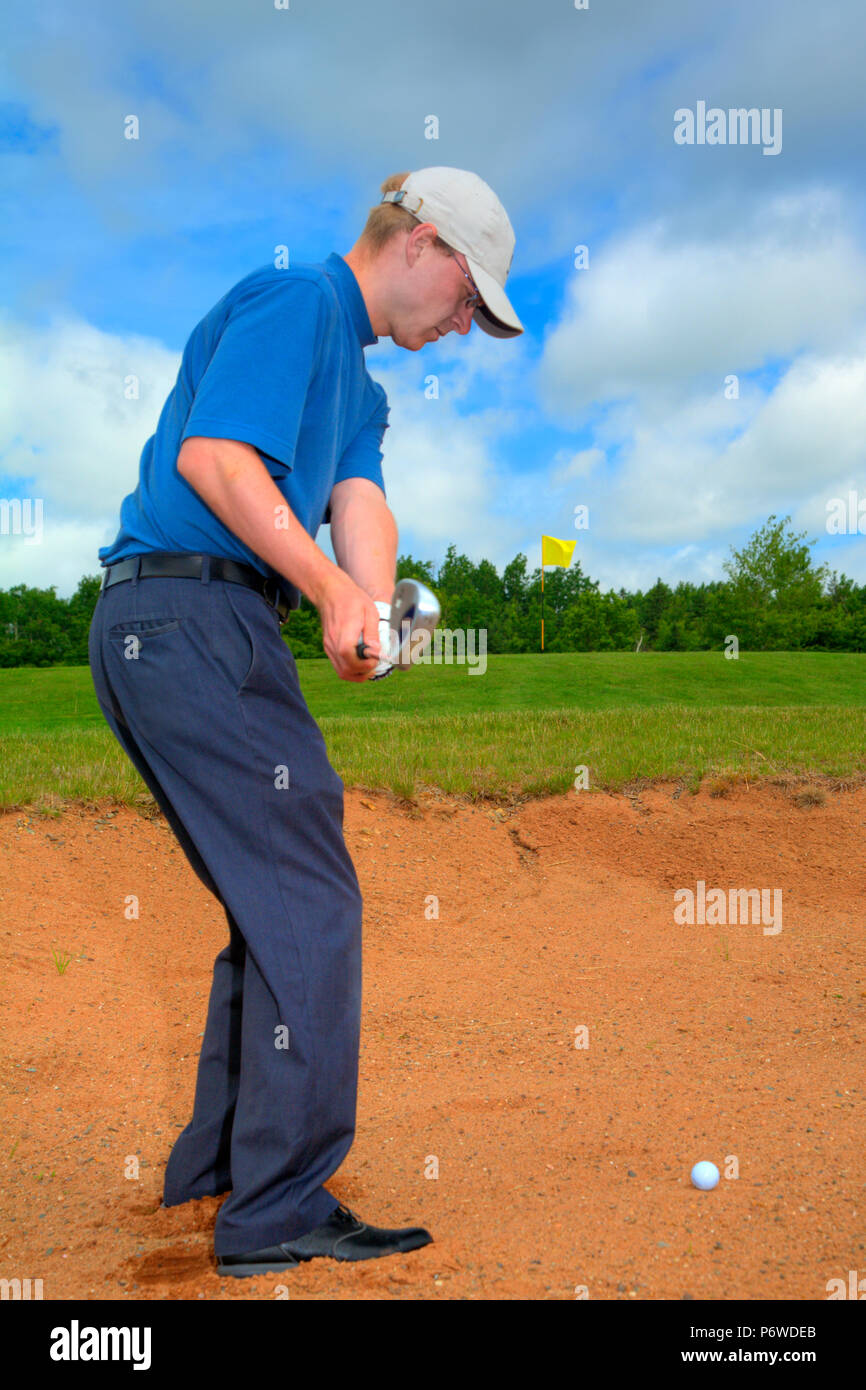 A golfer begins the stroke to exit from a sand trap Stock Photo - Alamy