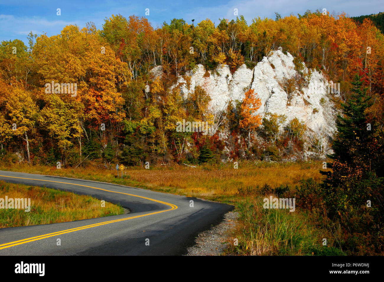 A sharp bend in the road by white cliffs and autumn colors in Mabou ...