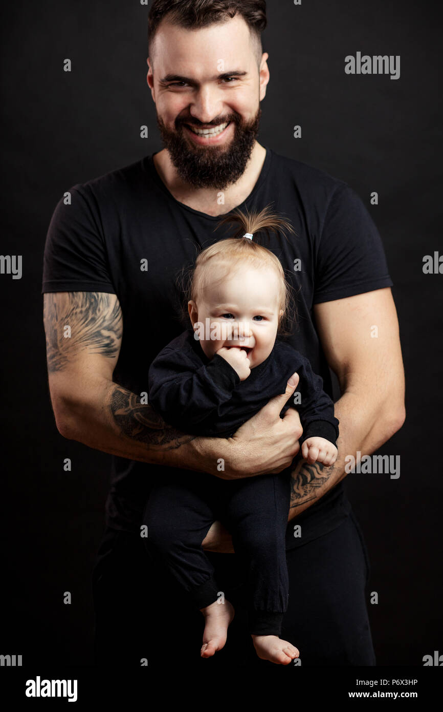 Young athletic beared father with adorable baby looking at camera on ...