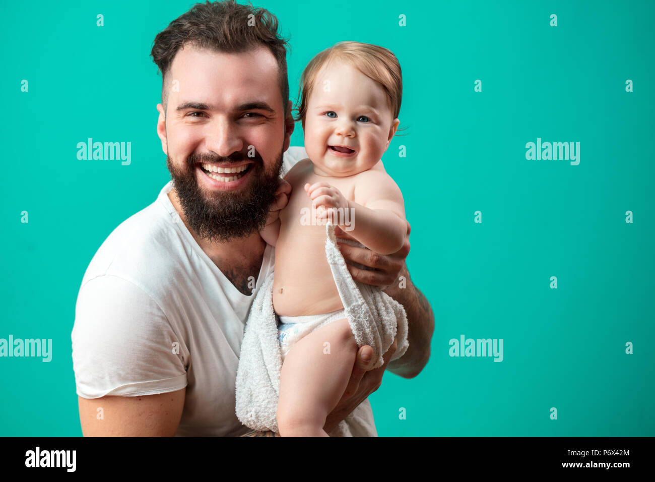 Portrait of young happy masculine father with his laugging chubby baby ...
