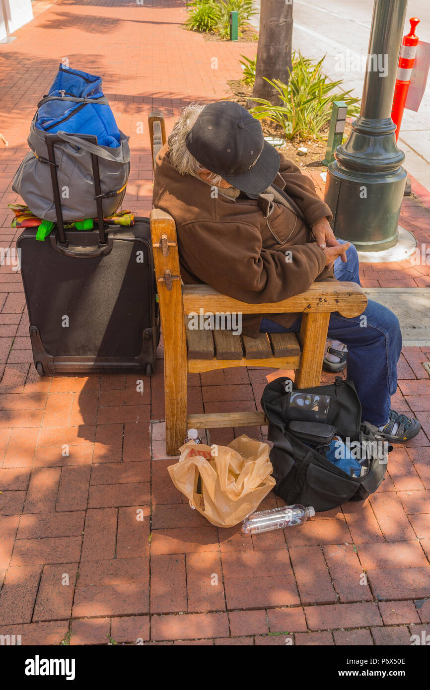 An older male vagrant takes a midday nap on a city bench Stock Photo ...