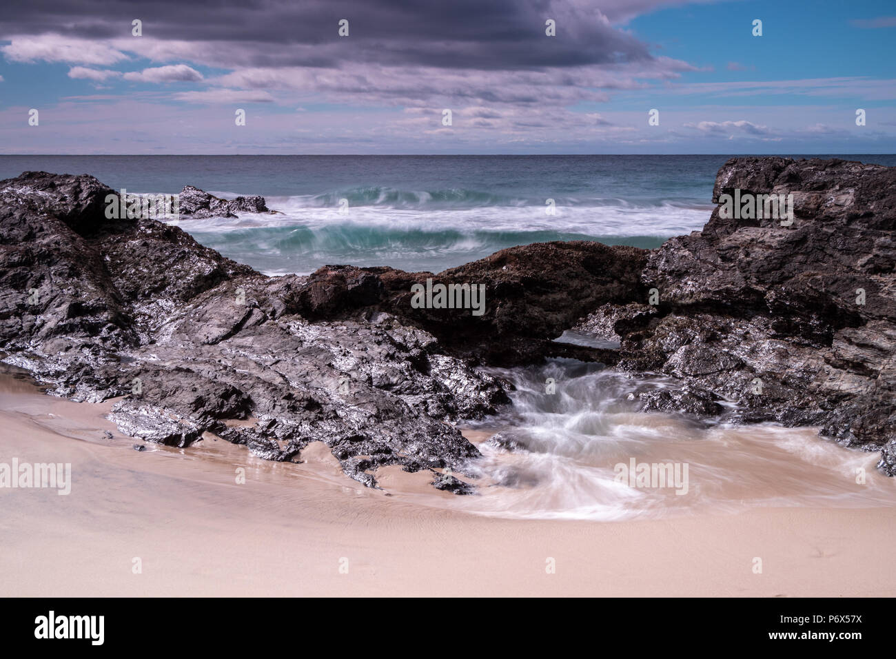 Surf hitting the rocks on a beach Stock Photo - Alamy