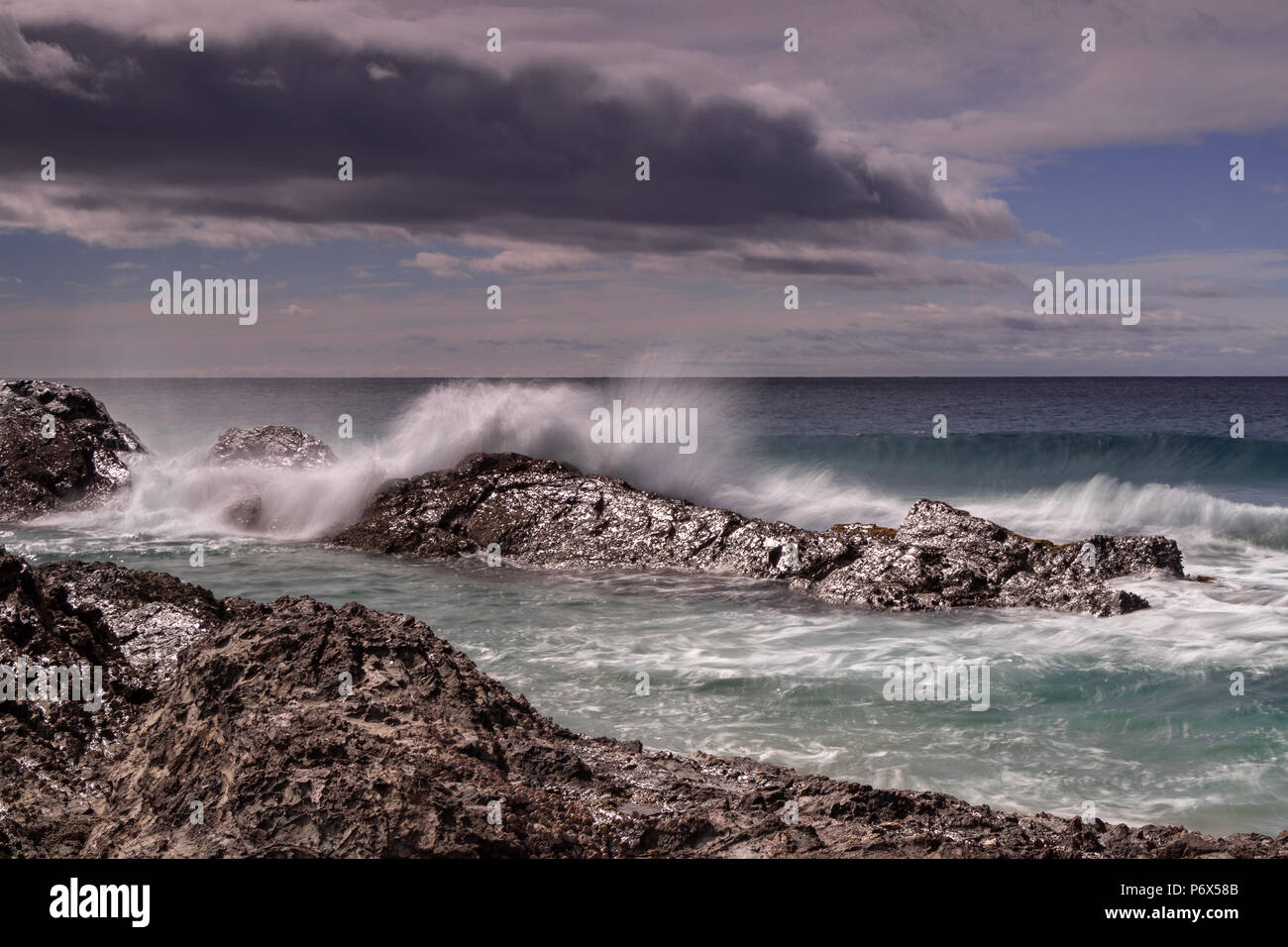 Surf hitting the rocks on a beach Stock Photo - Alamy