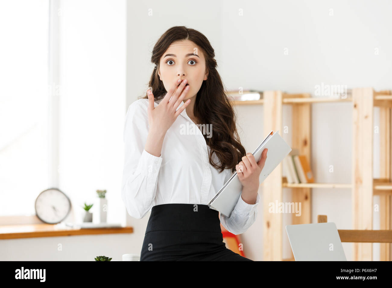 Shocked young business woman surprised by reading unexpected news in ...