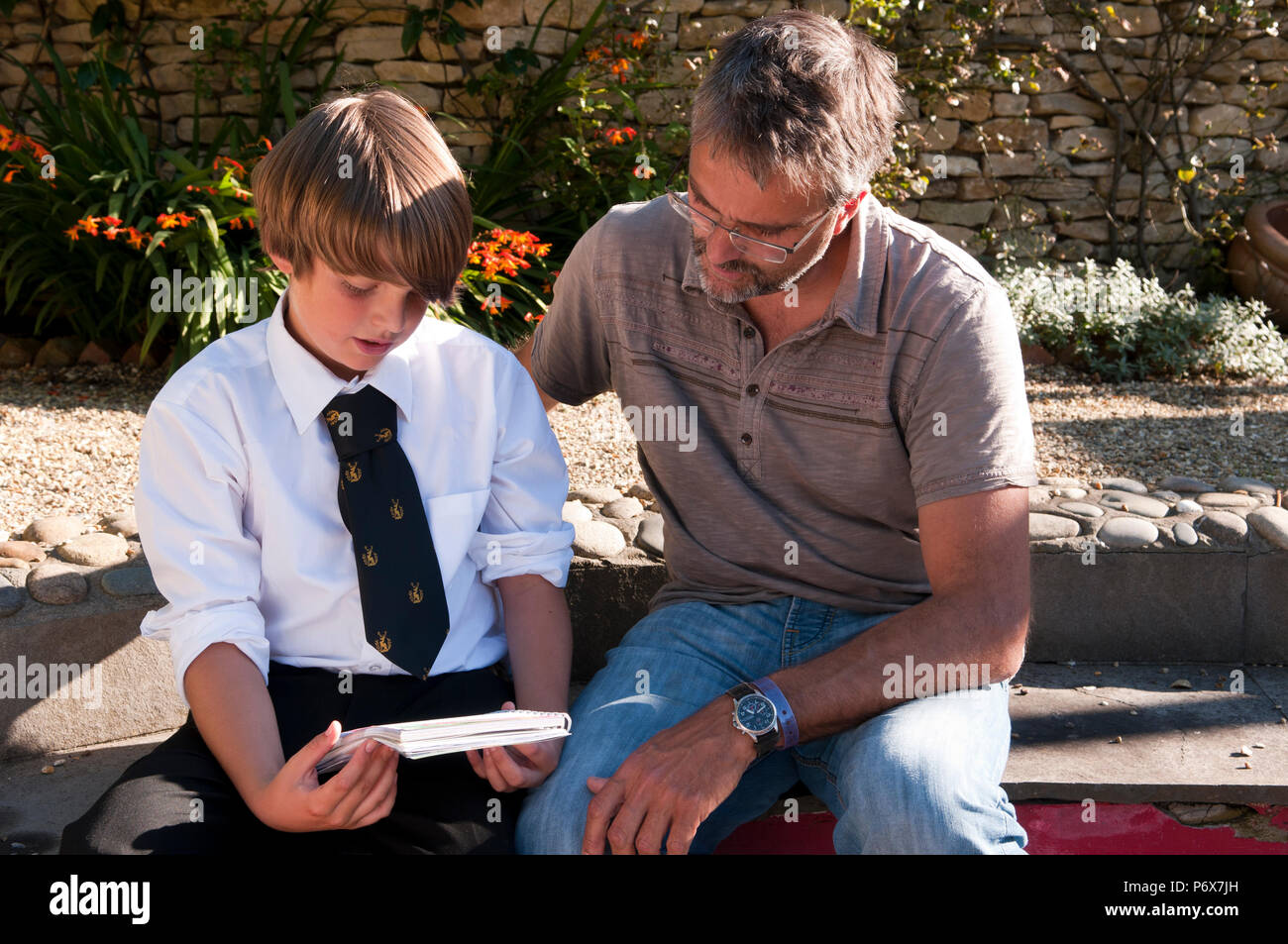 Schoolboy sitting in garden showing his father his schoolwork Stock ...