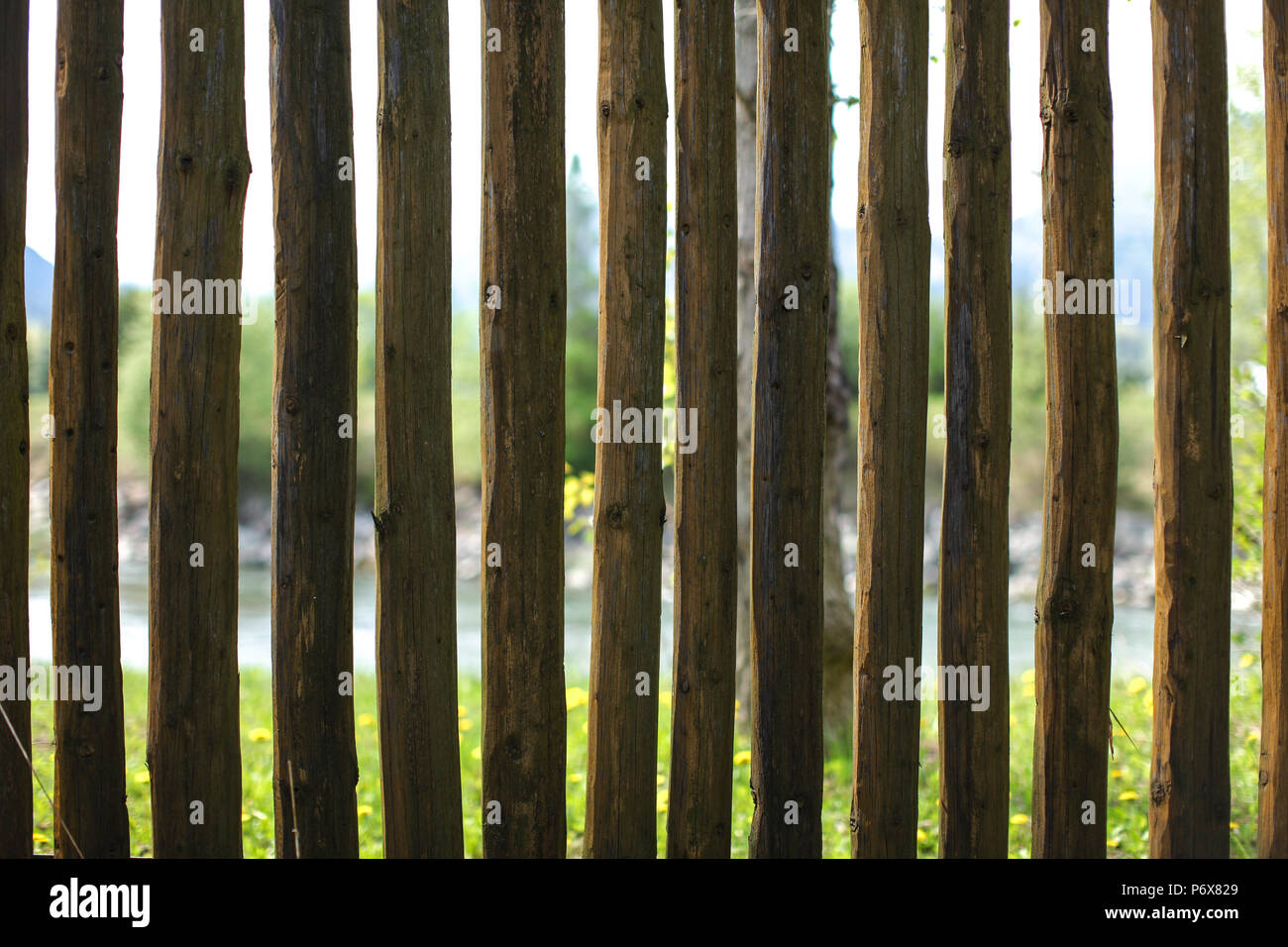 Old wooden fence posts, with blurred river out of focus in background ...