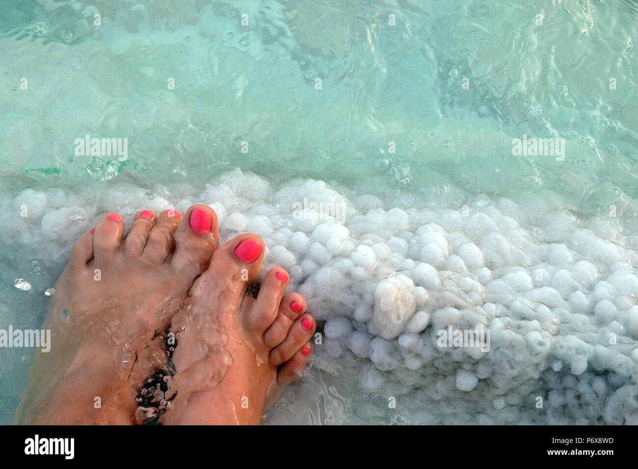 Female feet with manicure on stone, covered with salt formations ...
