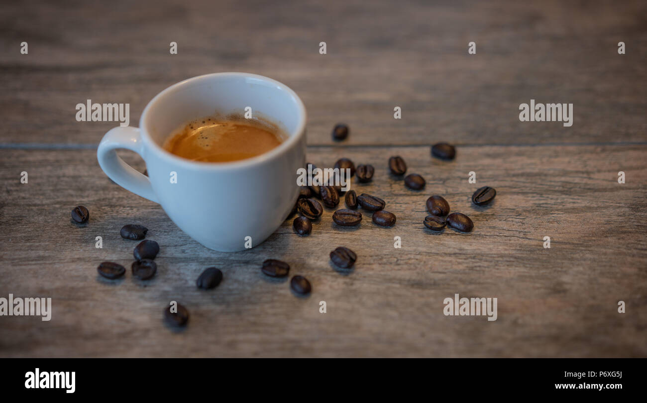 Espresso with crema in a white cup with coffee beans on a light wood ...