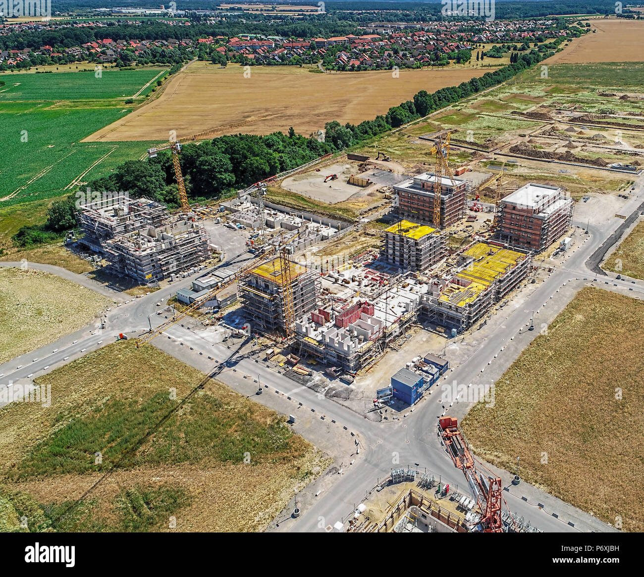 Large construction site on the outskirts behind a village with meadows ...