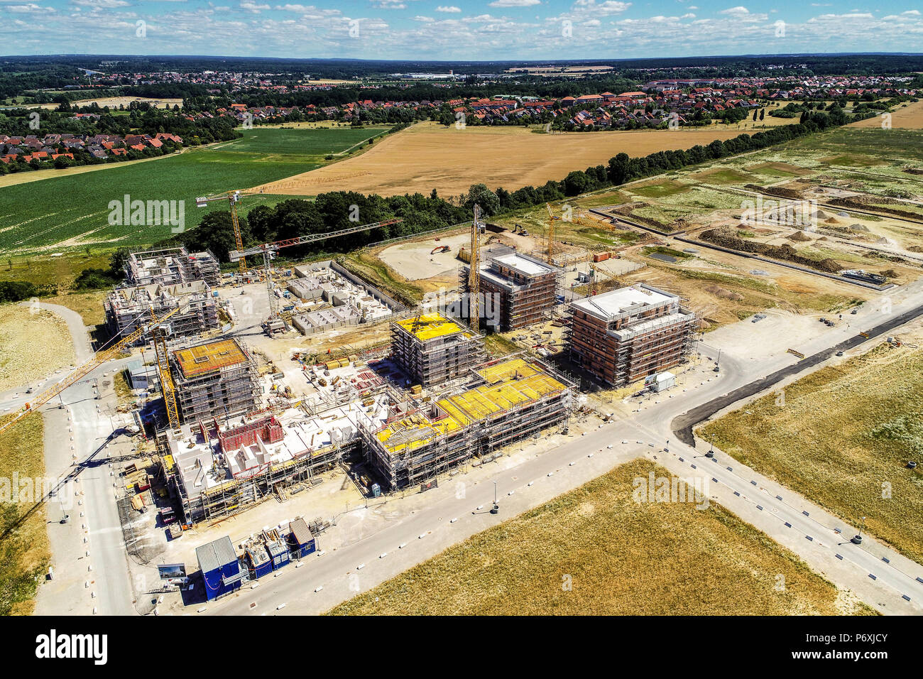 Large construction site on the outskirts behind a village with meadows ...