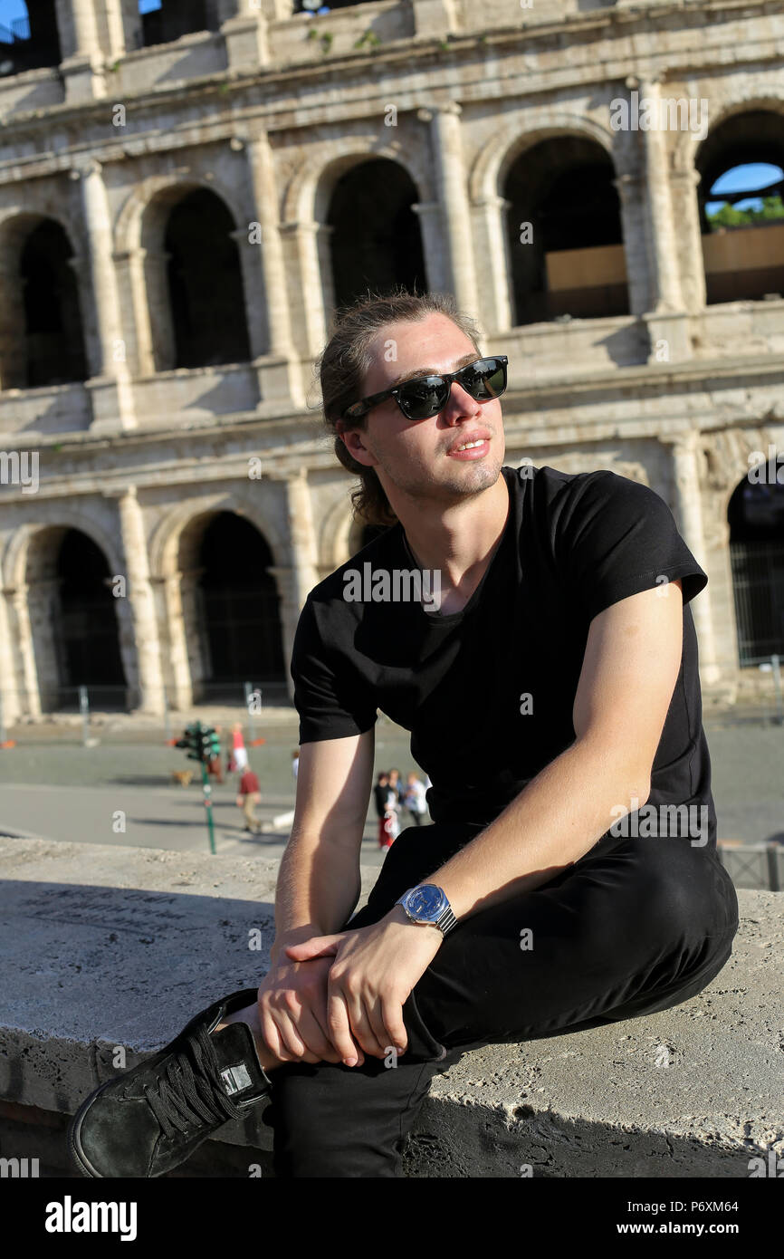 Young man sitting near Colosseum background in Rome, Italy Stock Photo ...