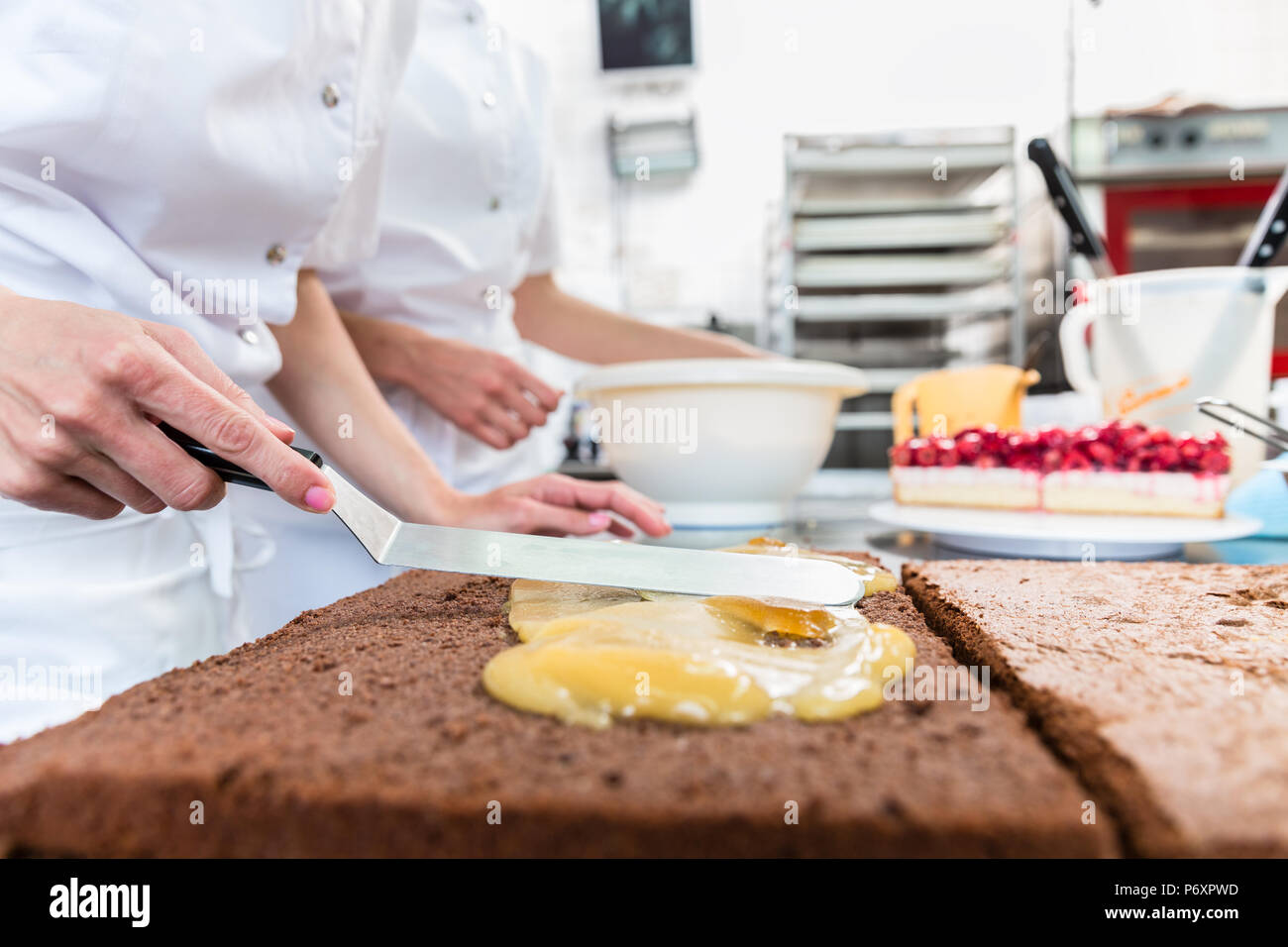 Confectioner woman getting chocolate cake ready with topping Stock ...