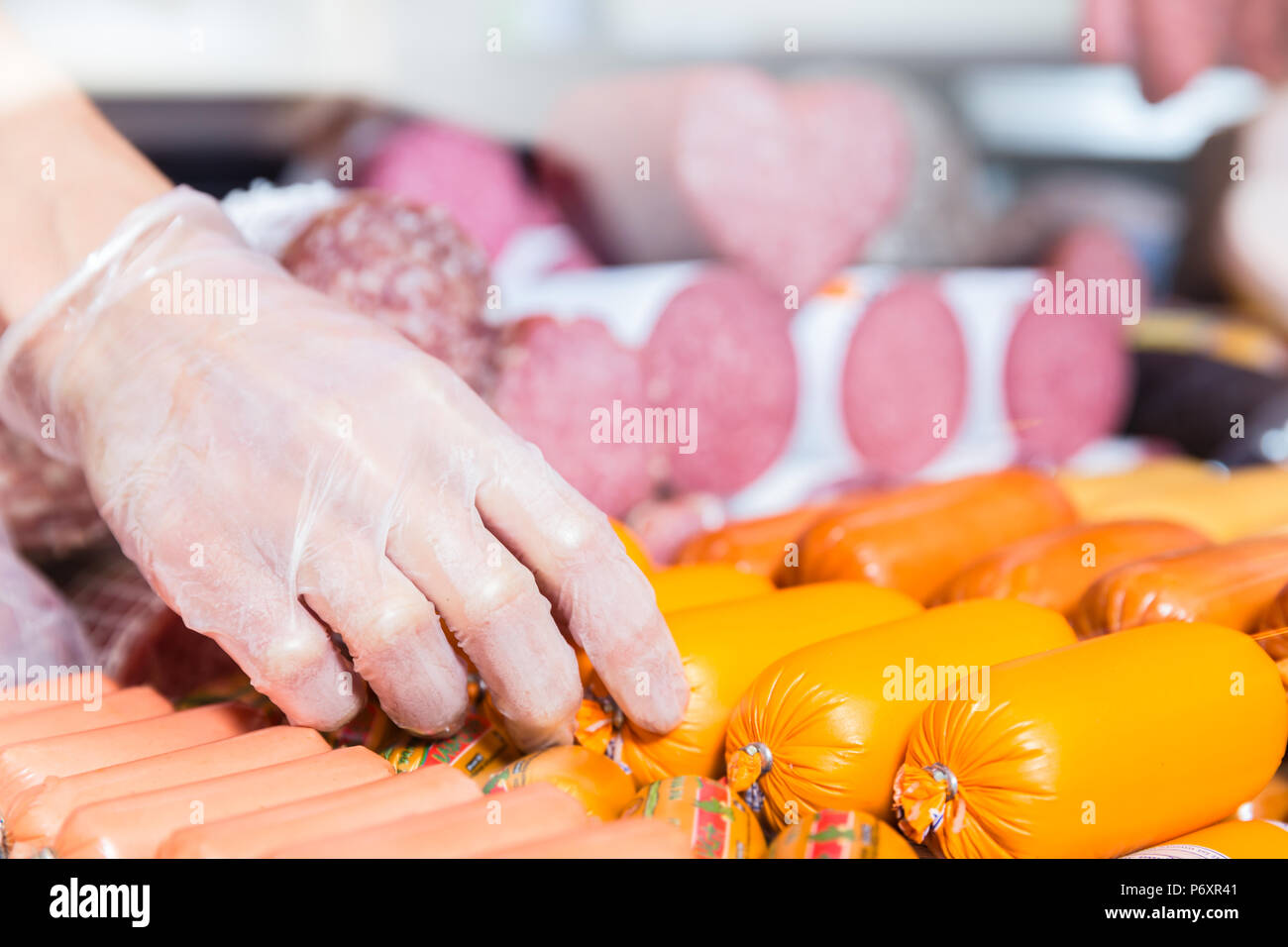 Woman putting sausages and meat in butcher shop display Stock Photo - Alamy