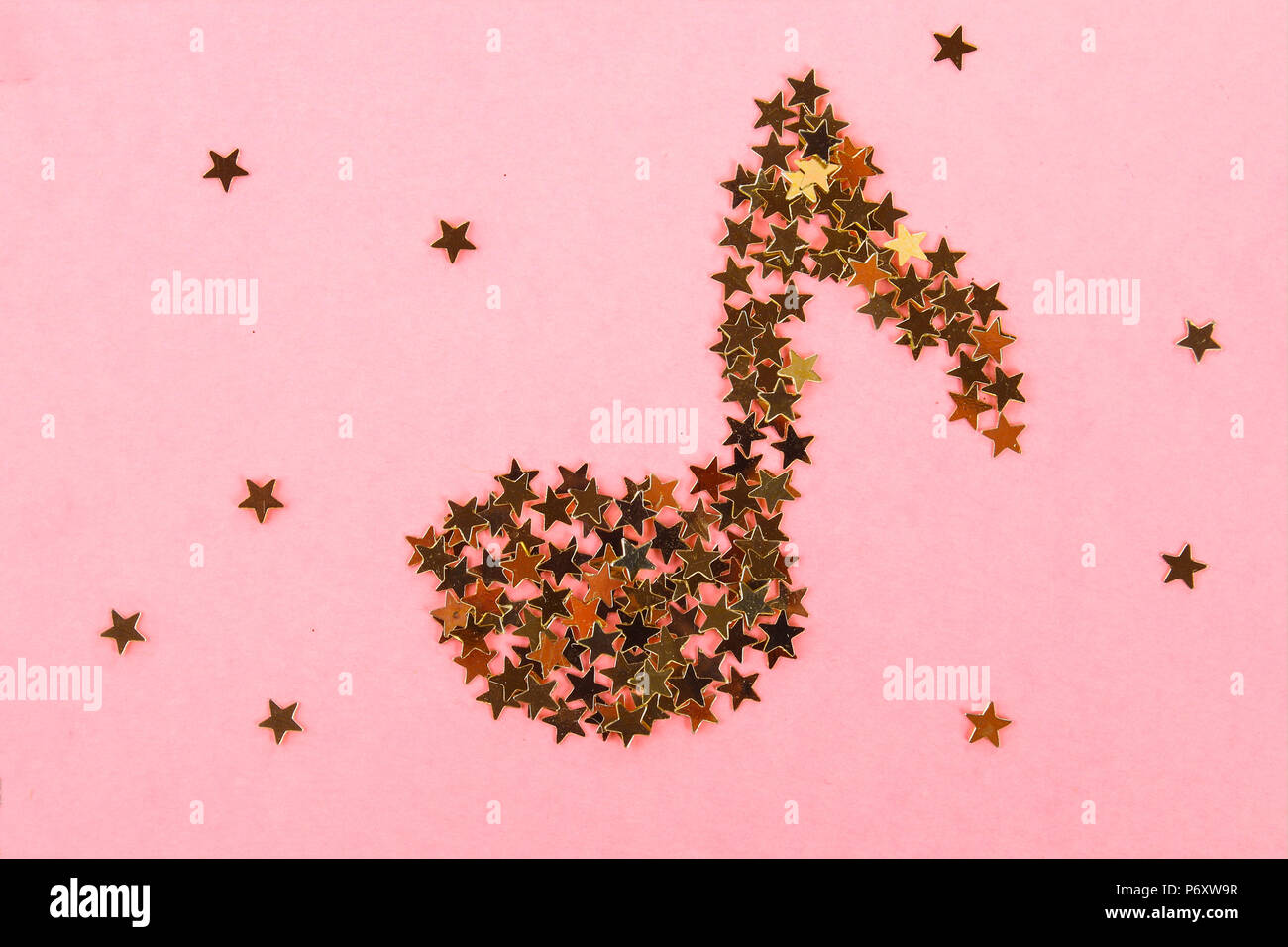Musical notes of starry golden confetti lying on a pink pastel ...