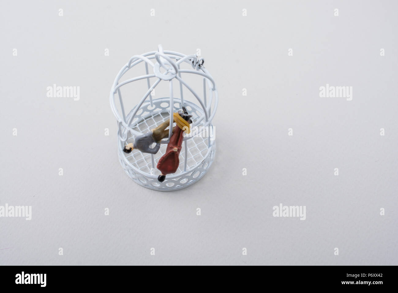 Tiny figurine of men wrapped in rope on a cage Stock Photo - Alamy