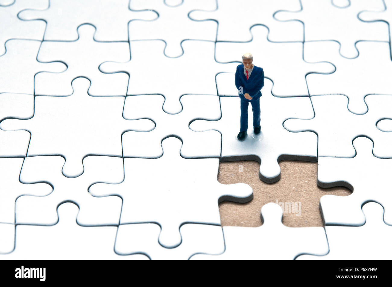 miniature figurine of a businessman standing on a jigsaw puzzle with a ...