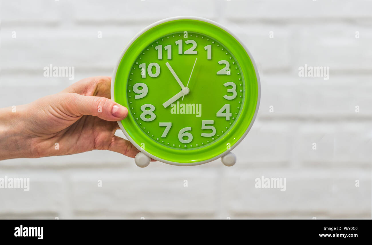 Green round clock in a female hand on a white background Stock Photo ...