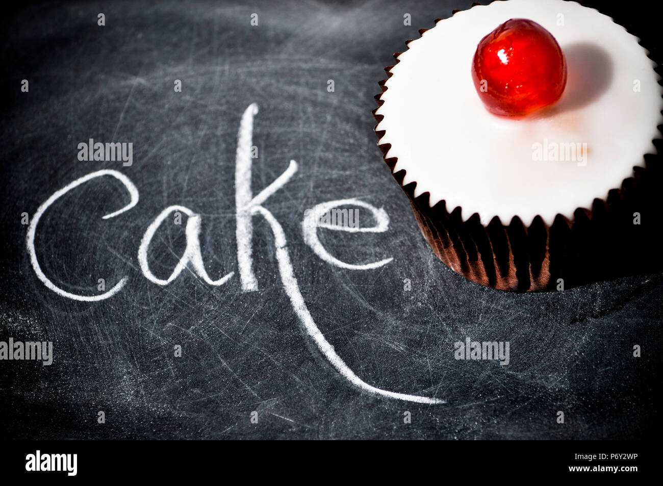 A blackboard with the word 'cake' written in chalk and a cherry topped ...