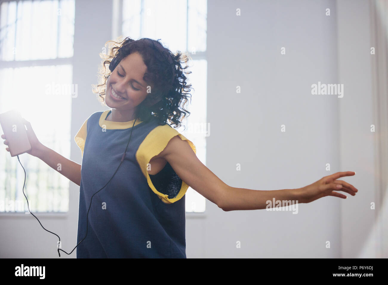 Carefree young female dancer listening to music with headphones and mp3 ...