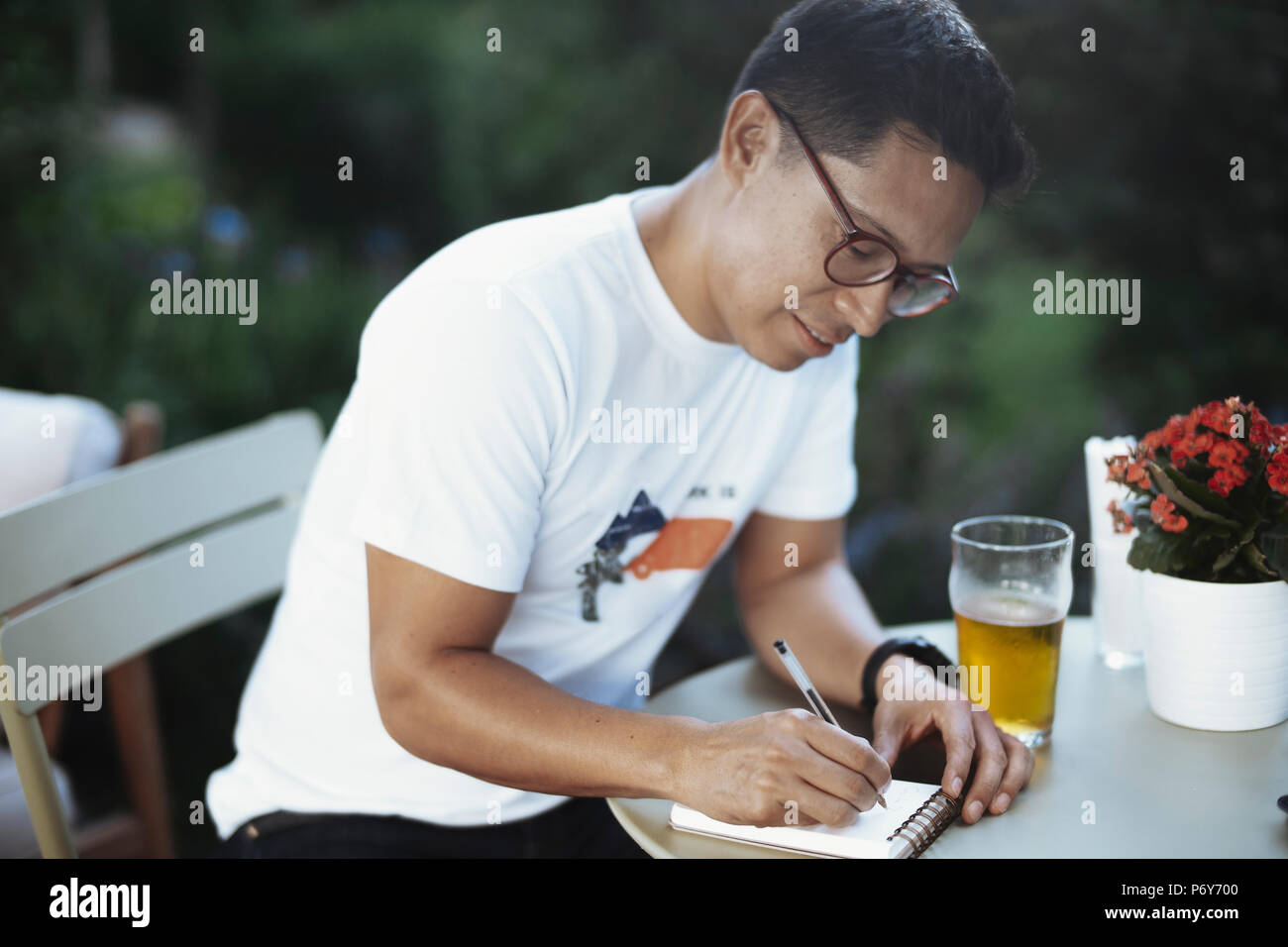 Young spectacled man drinking cold beer and writing some notes Stock ...