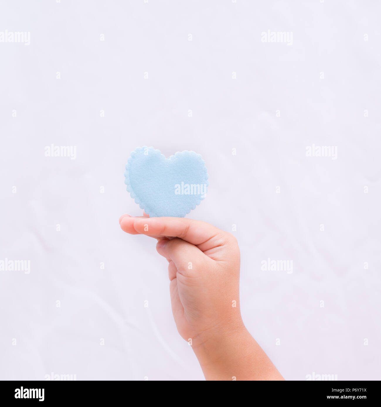 Blue heart in hand on white background Stock Photo - Alamy