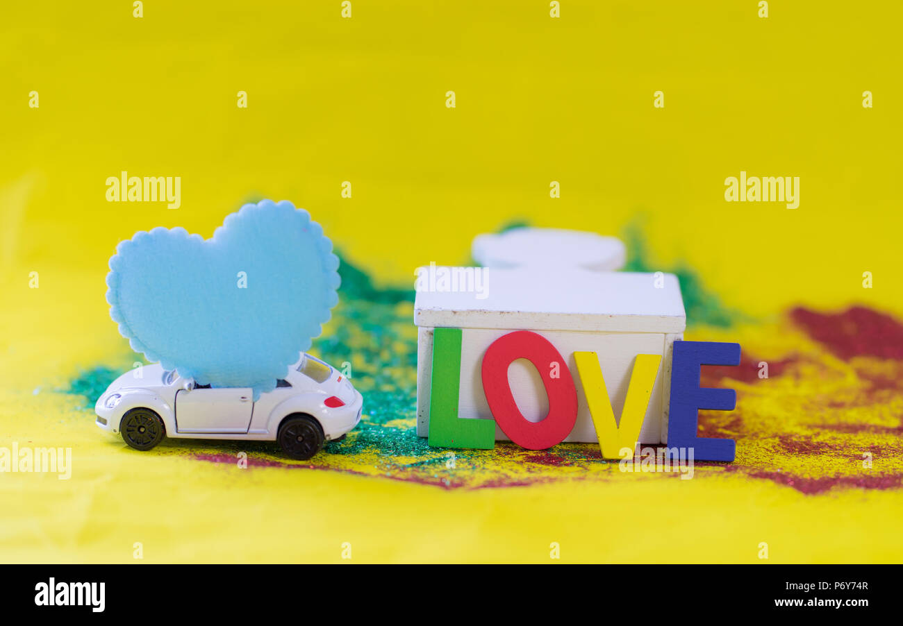 Blue heart on white toy car, alphabet Love on yellow paper background ...