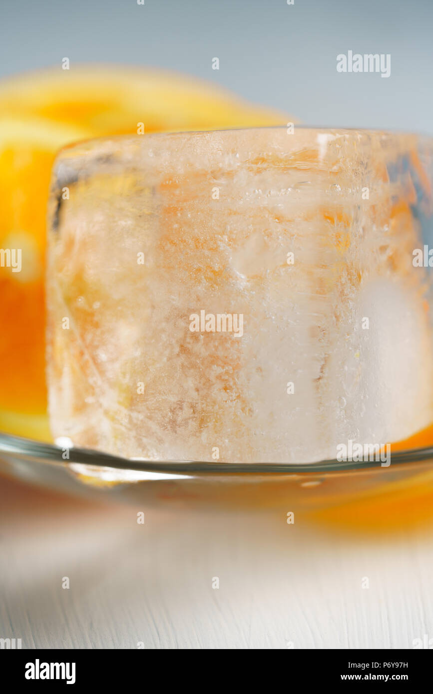 Ice cube with orange slices on a glass plate. Macro shot, high ...