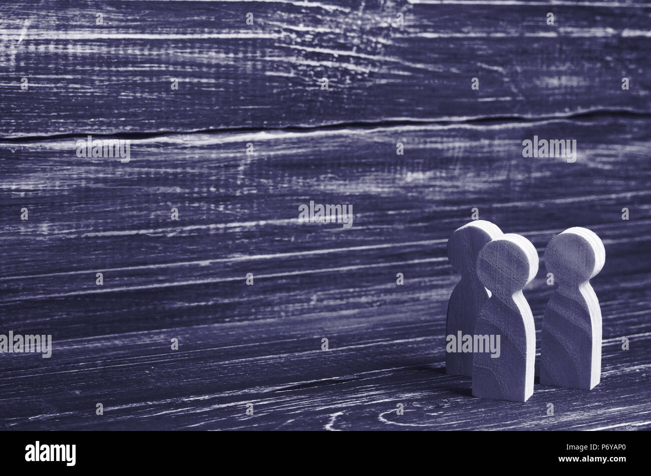 Three wooden human figures stand together. Social concept, family, team ...