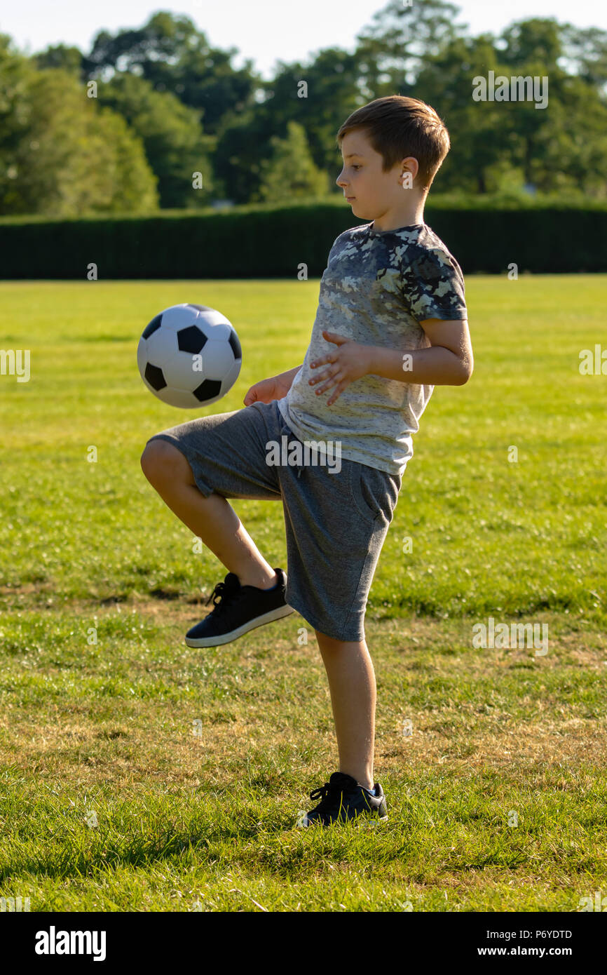 Pre-teen boy playing with a football in a park Stock Photo - Alamy