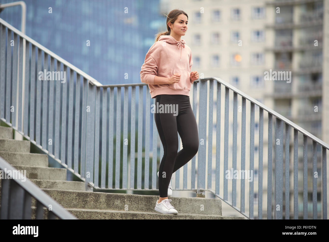 Fit pretty girl running up stairs with city background Stock Photo - Alamy
