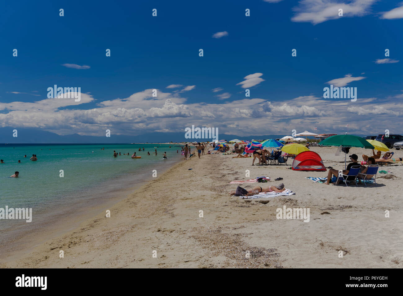 Greek Mediterranean beach with crowd. Bathers with sun umbrellas at a ...