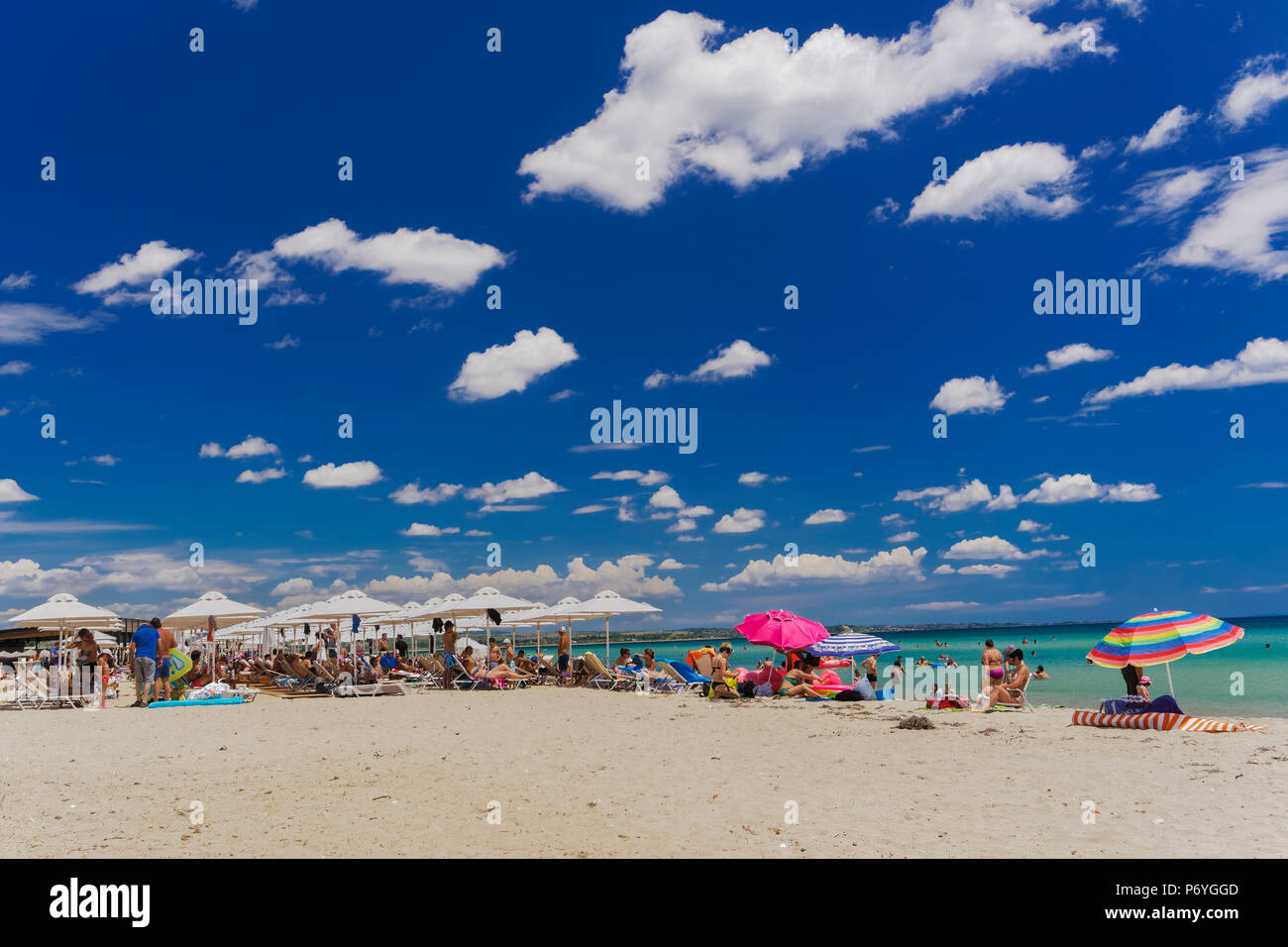 Greek Mediterranean beach bar with crowd. Bathers with sun umbrellas at ...