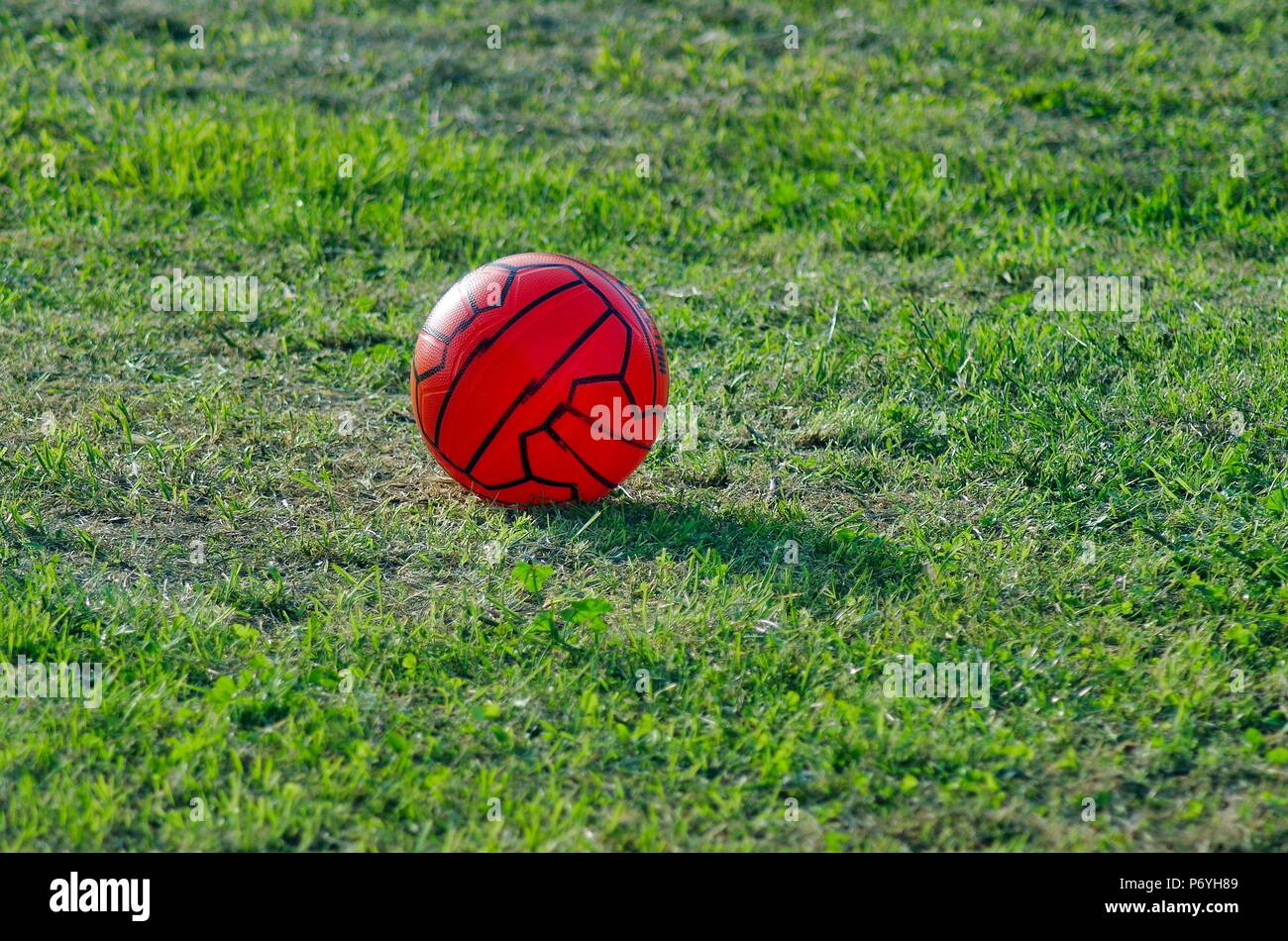 a red soccer ball in the ground Stock Photo - Alamy