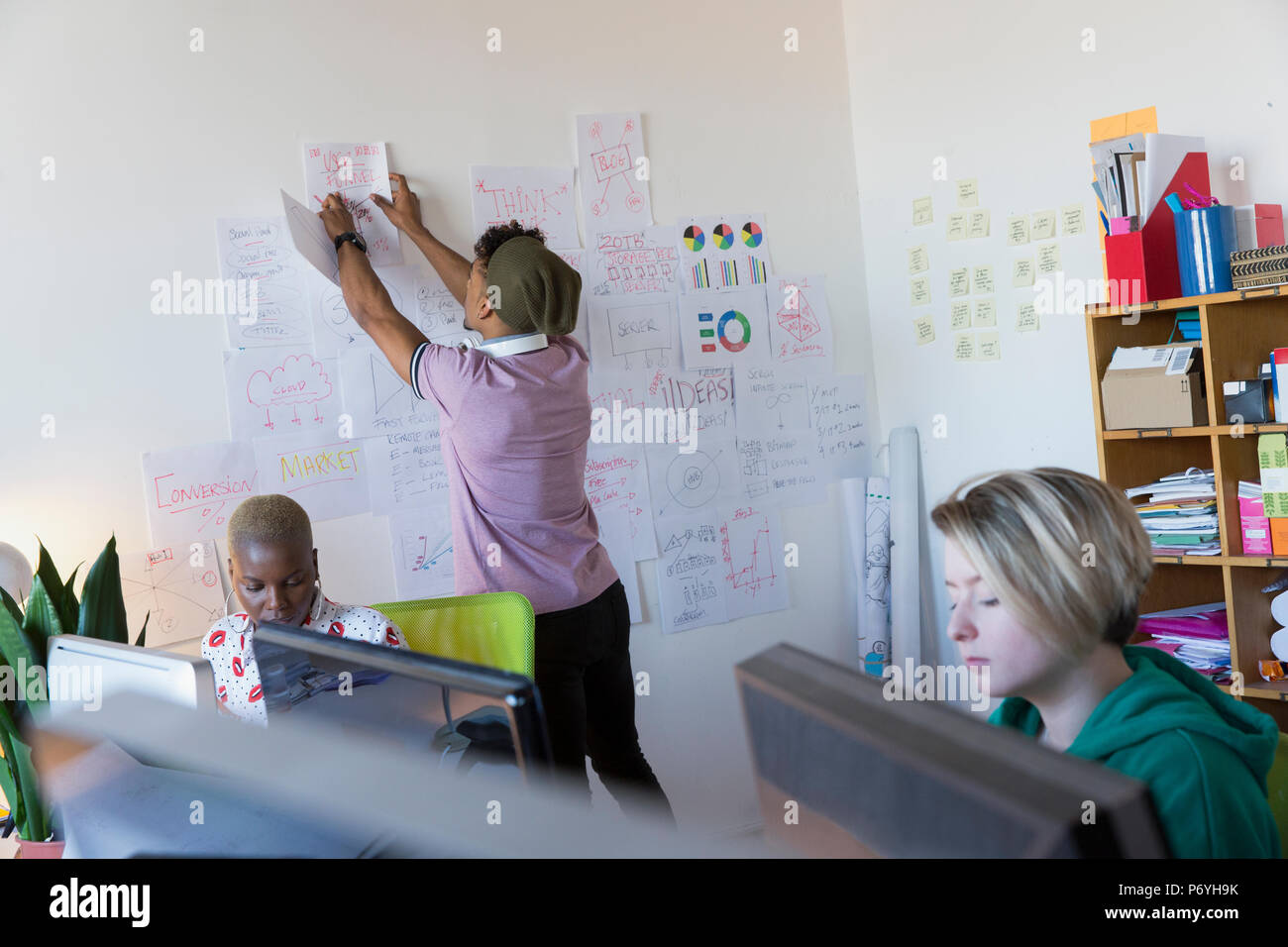 Creative businessman hanging paperwork on office wall Stock Photo - Alamy