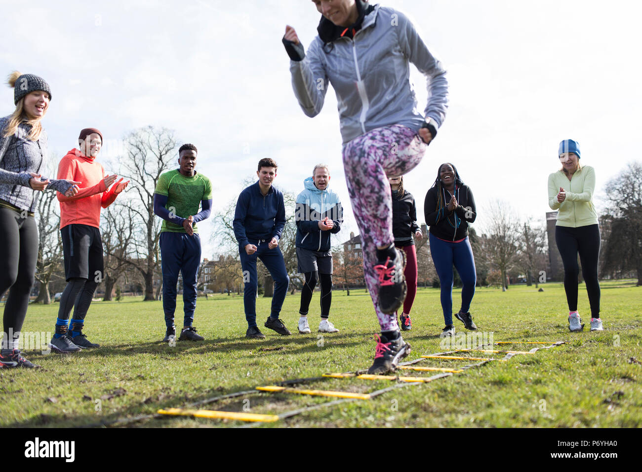 Team cheering woman doing speed ladder drill in sunny park Stock Photo ...