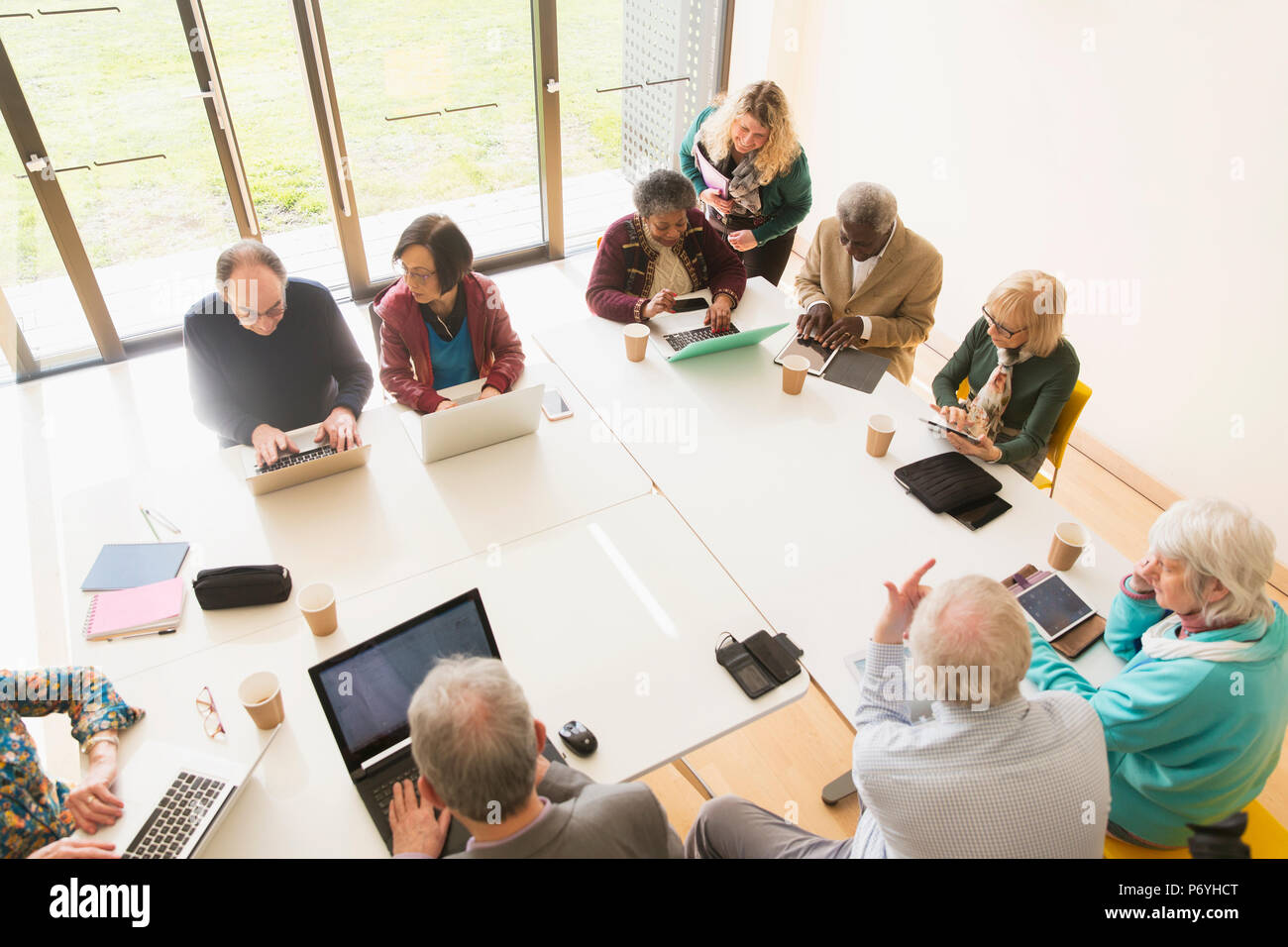 Senior business people using laptops and digital tablets in conference ...