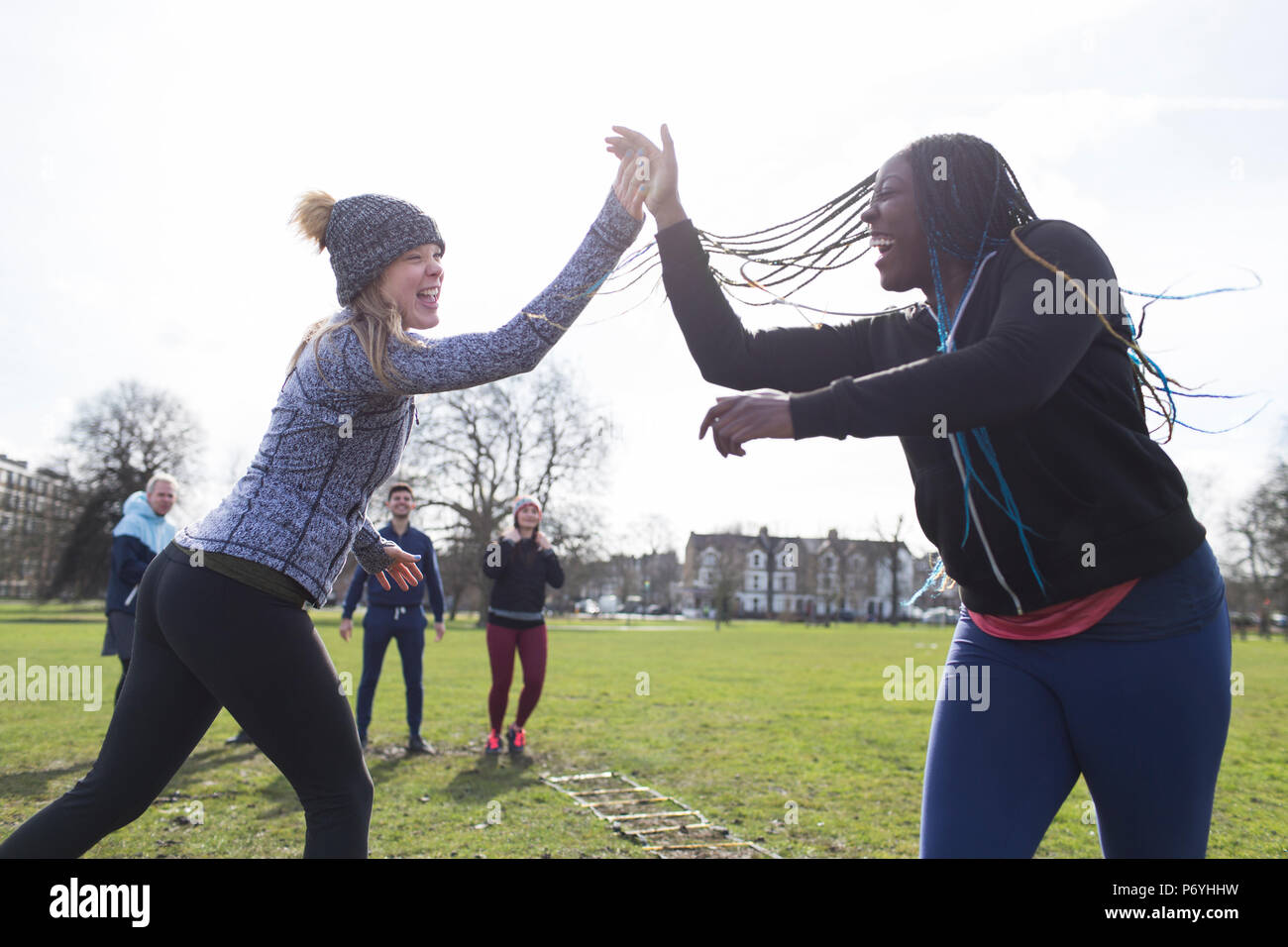 Enthusiastic women high-fiving, exercising in sunny park Stock Photo ...