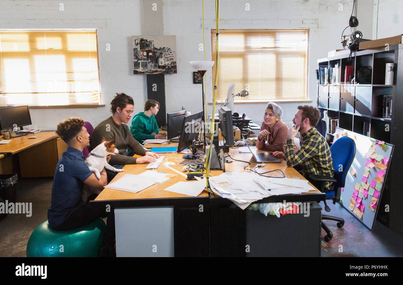Creative business people working, meeting at computers in open plan ...