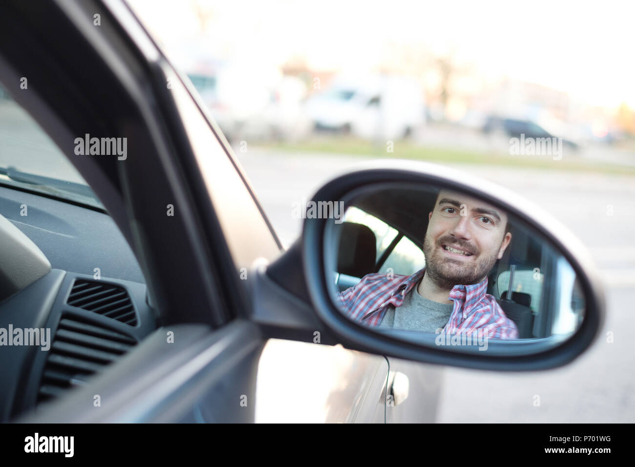 Young car driver looking to the road side view mirror.Safe trip journey ...