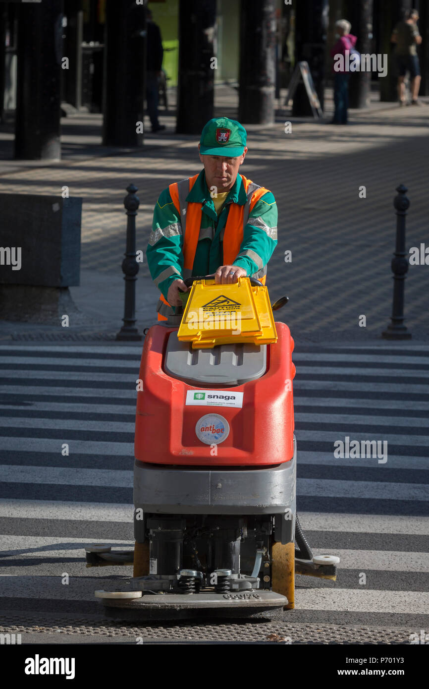 A city street cleaning operator drives his small vehicle along ...
