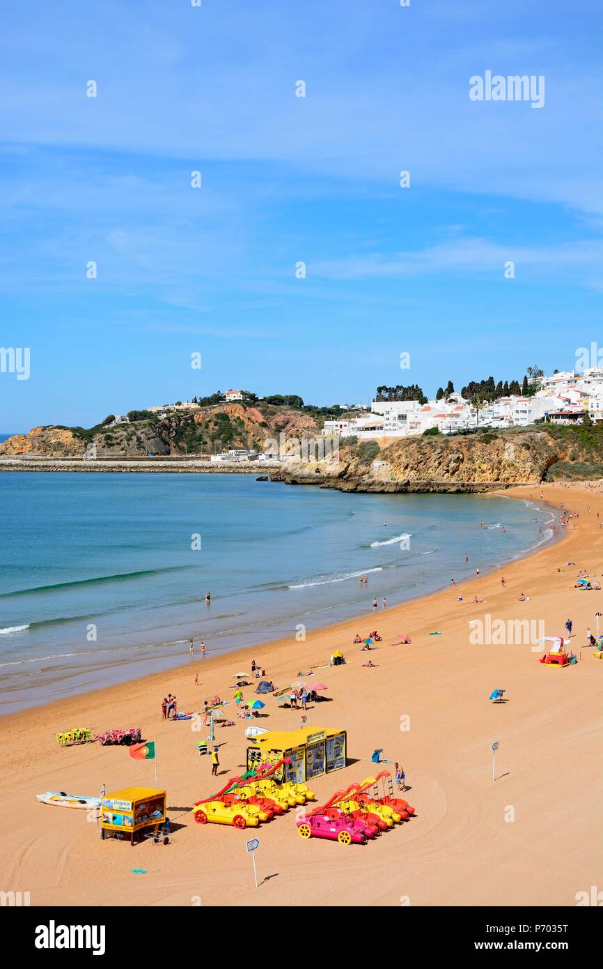 Elevated view of tourists relaxing on the beach with town buildings to ...
