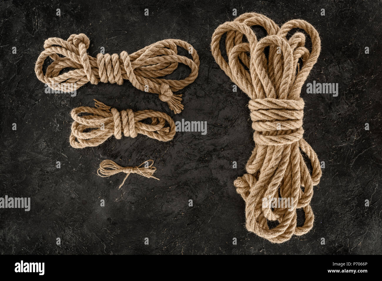 top view of arrangement of tied brown marine ropes on dark concrete ...